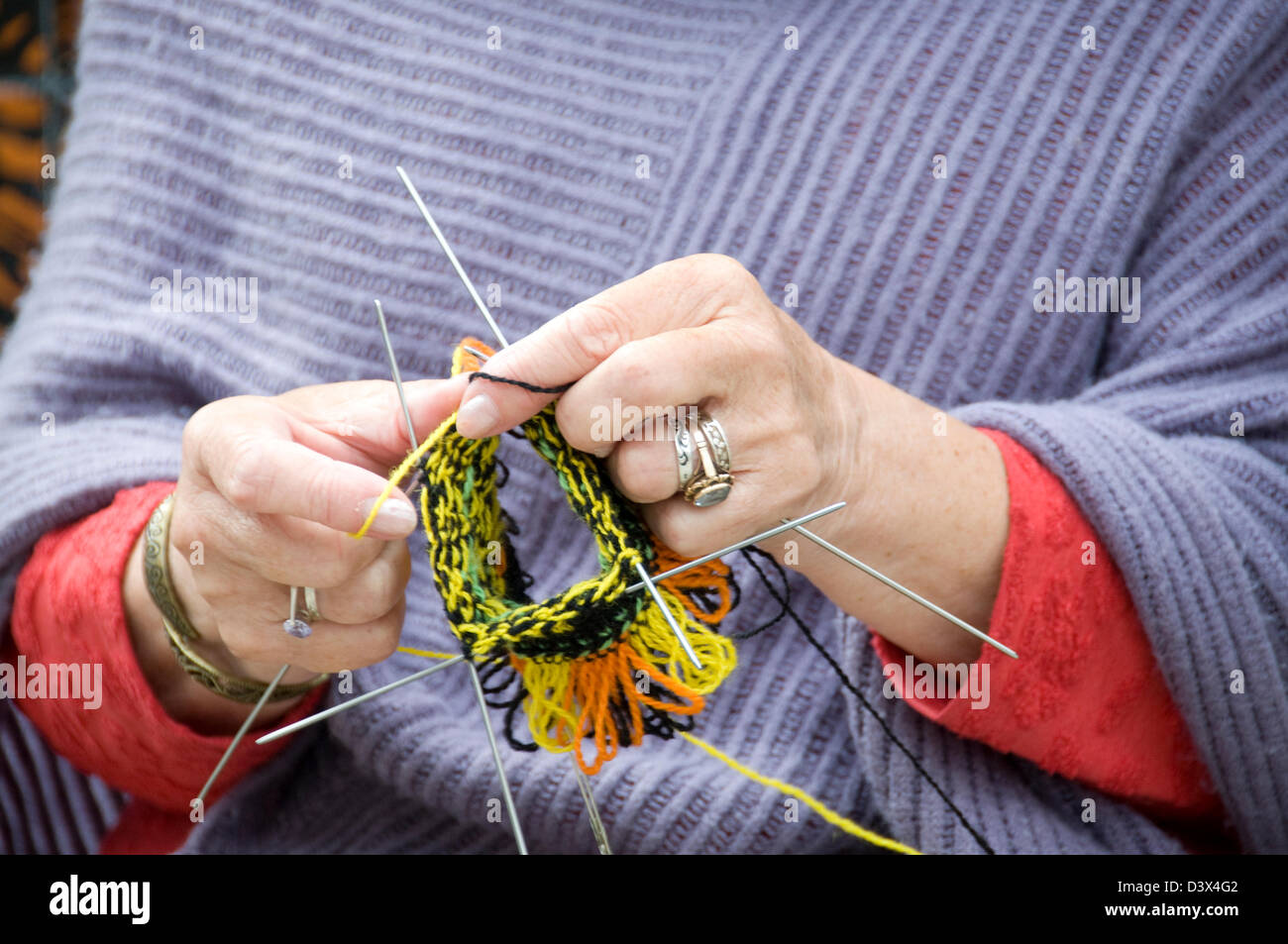 A stall holder, knitting a garment at a Russian market on Skanmu iela ...