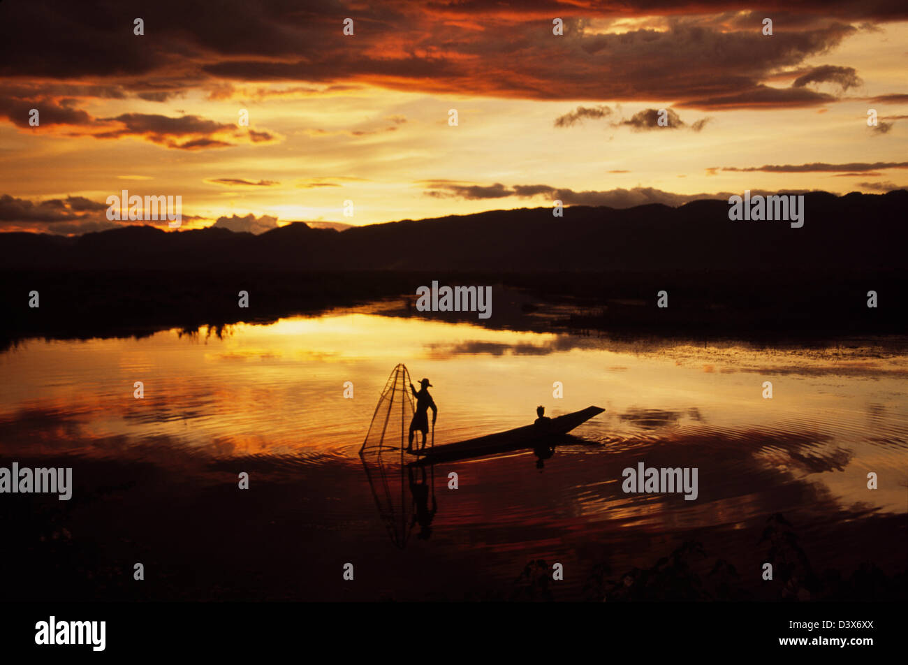 Intha fisherman rowing boat with legs and fishing at sunset, Inle Lake ...