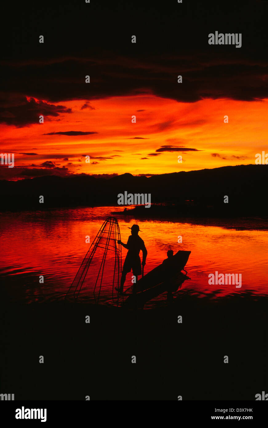 Intha fisherman rowing boat with legs and fishing at sunset, Inle Lake ...