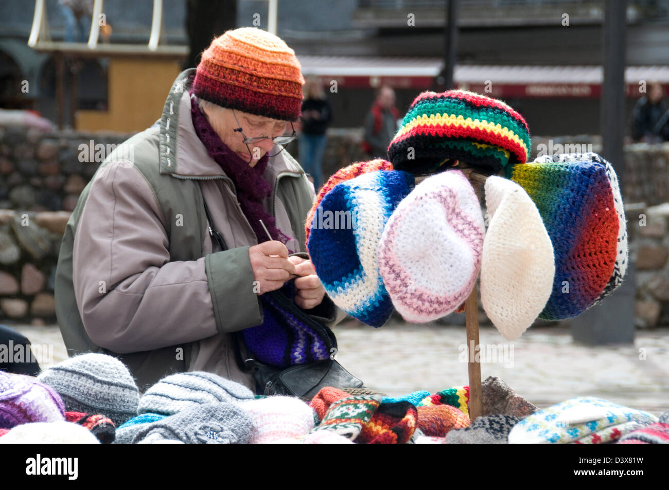 A stall holder, knitting a garment at a Russian market on Skanmu iela ...