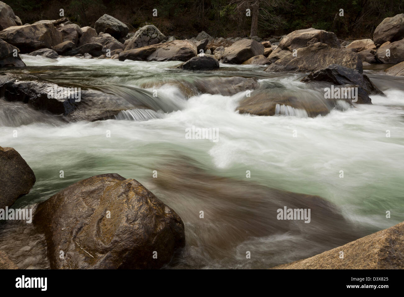 Silky slow motion river water flowing over and around large boulders in ...