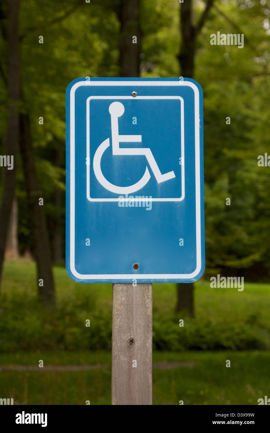 Light blue "accessible" disabled parking sign in before woods in the ...
