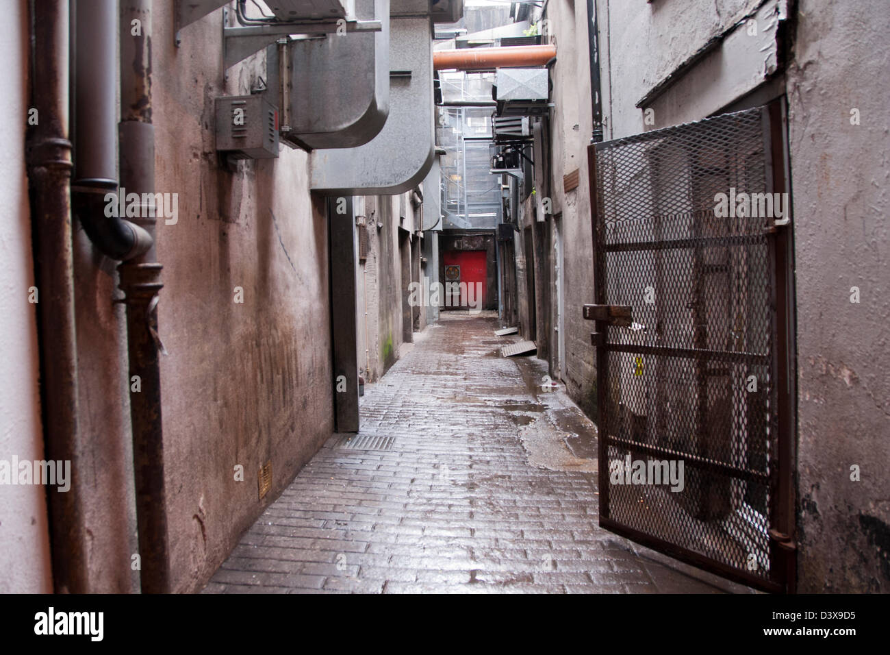 A view into an alleyway at the end of which sits a red door Stock Photo ...