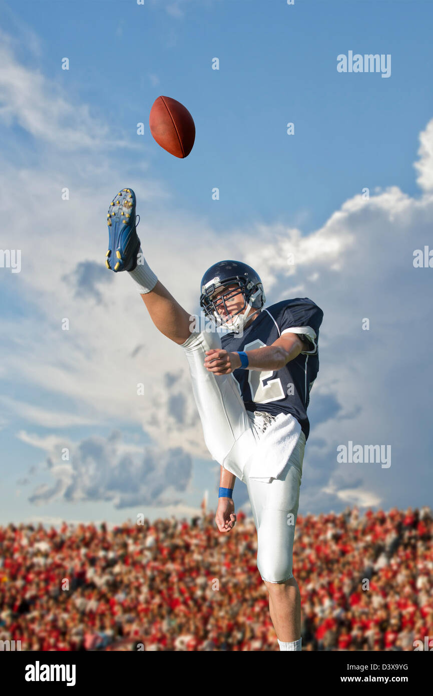Caucasian football player kicking ball Stock Photo - Alamy