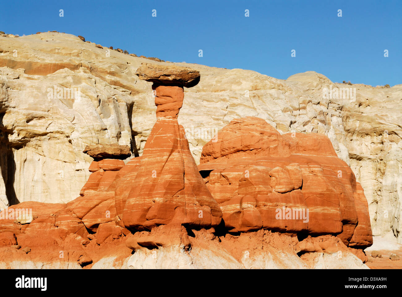 red Hoodoo rock spire contrasting against white sandstone cliffs at the ...