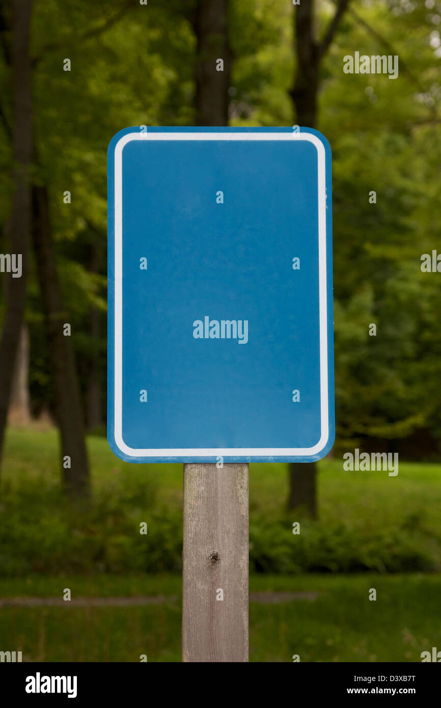 Empty light blue sign before a wooded background. Plenty of copy space ...