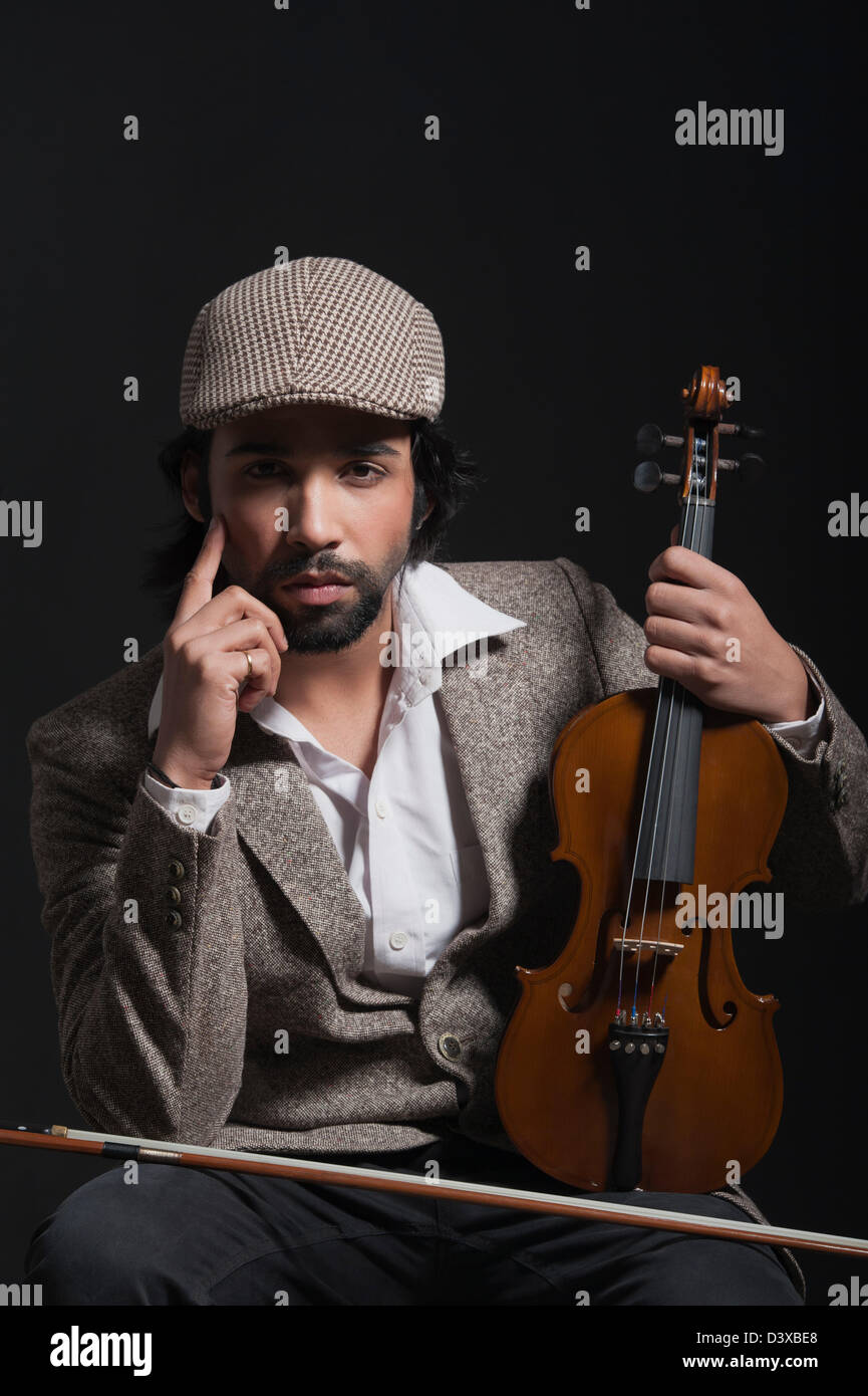 Musician holding a violin and thinking Stock Photo - Alamy