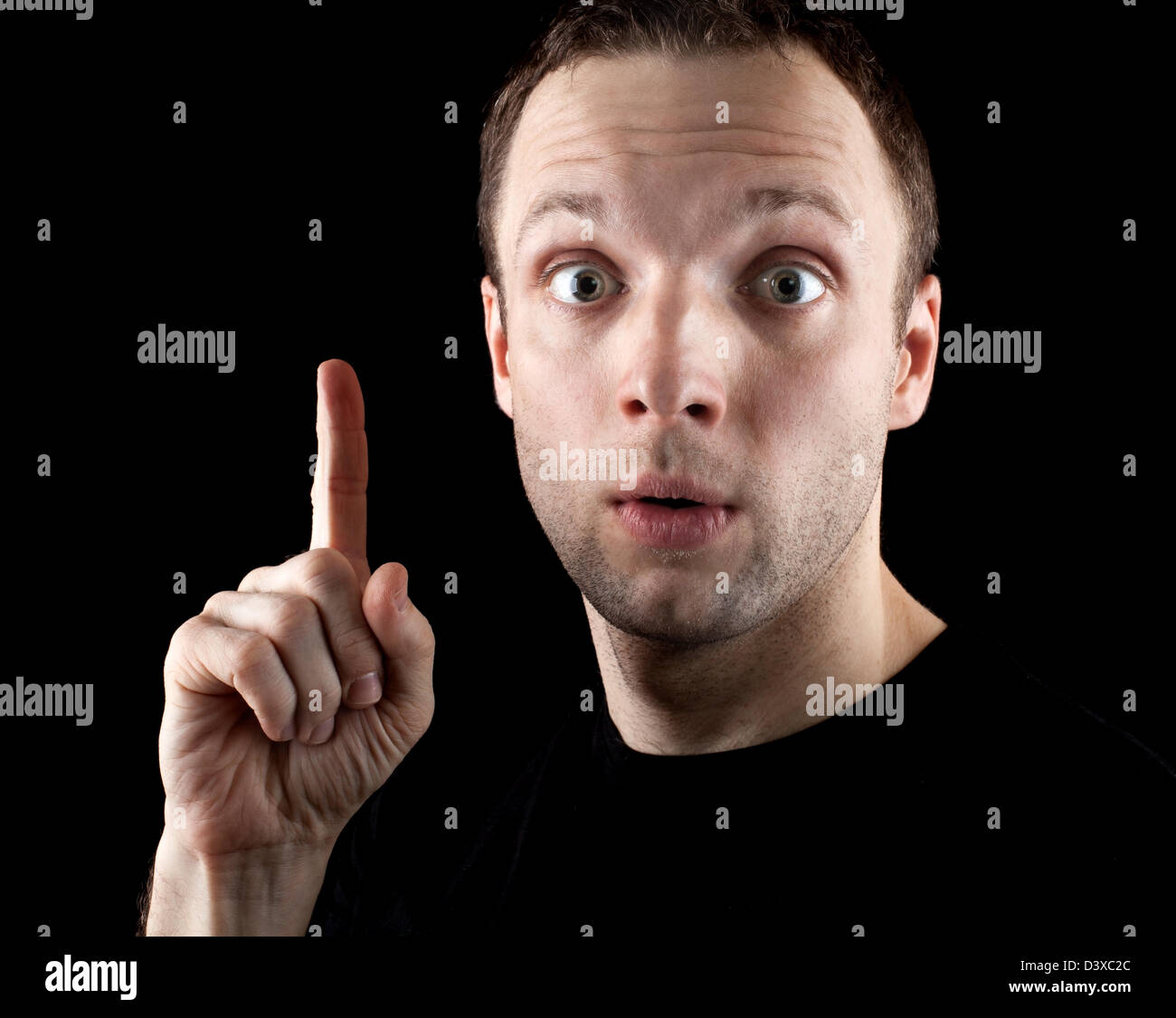 Surprised man with finger up idea gesture isolated on black background ...