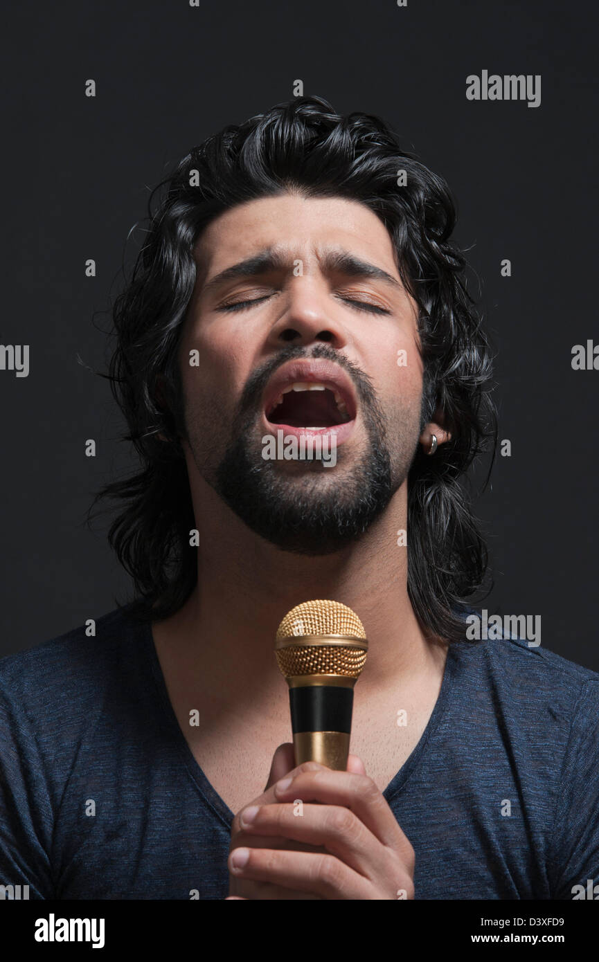 Singer holding a mike and singing Stock Photo - Alamy