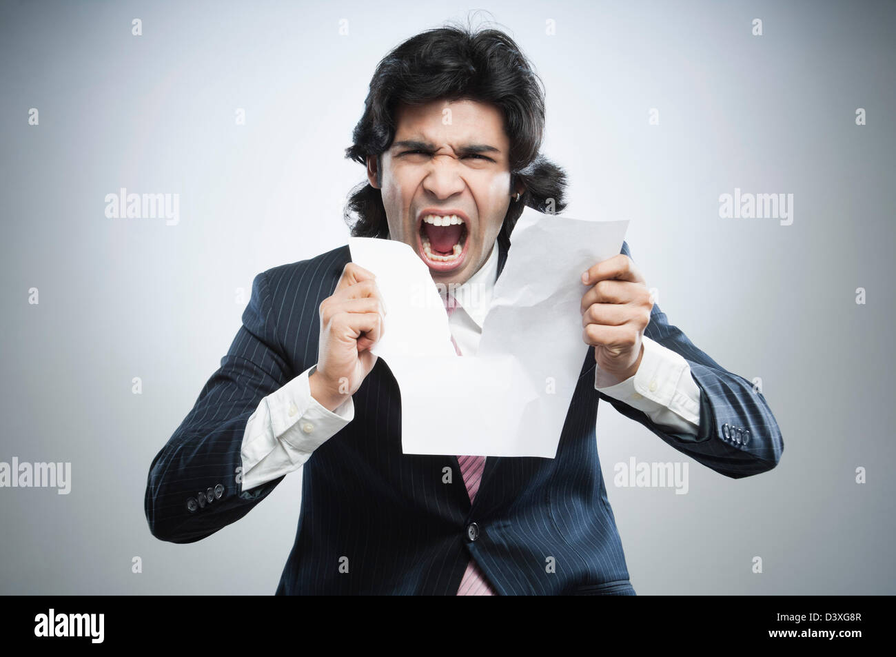 Angry businessman tearing a sheet of paper Stock Photo - Alamy