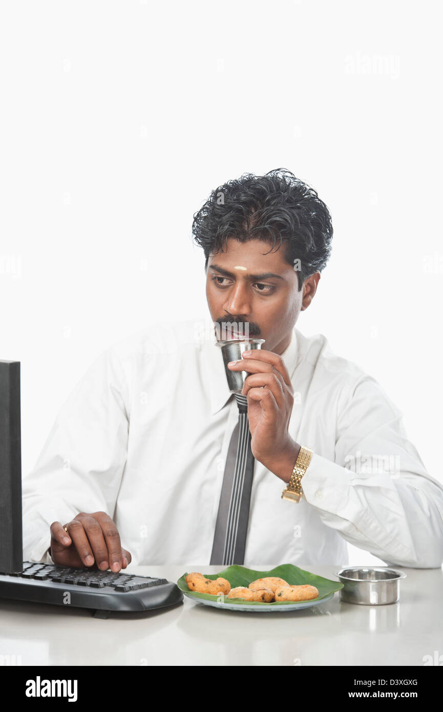 South Indian businessman working in an office and having food Stock ...