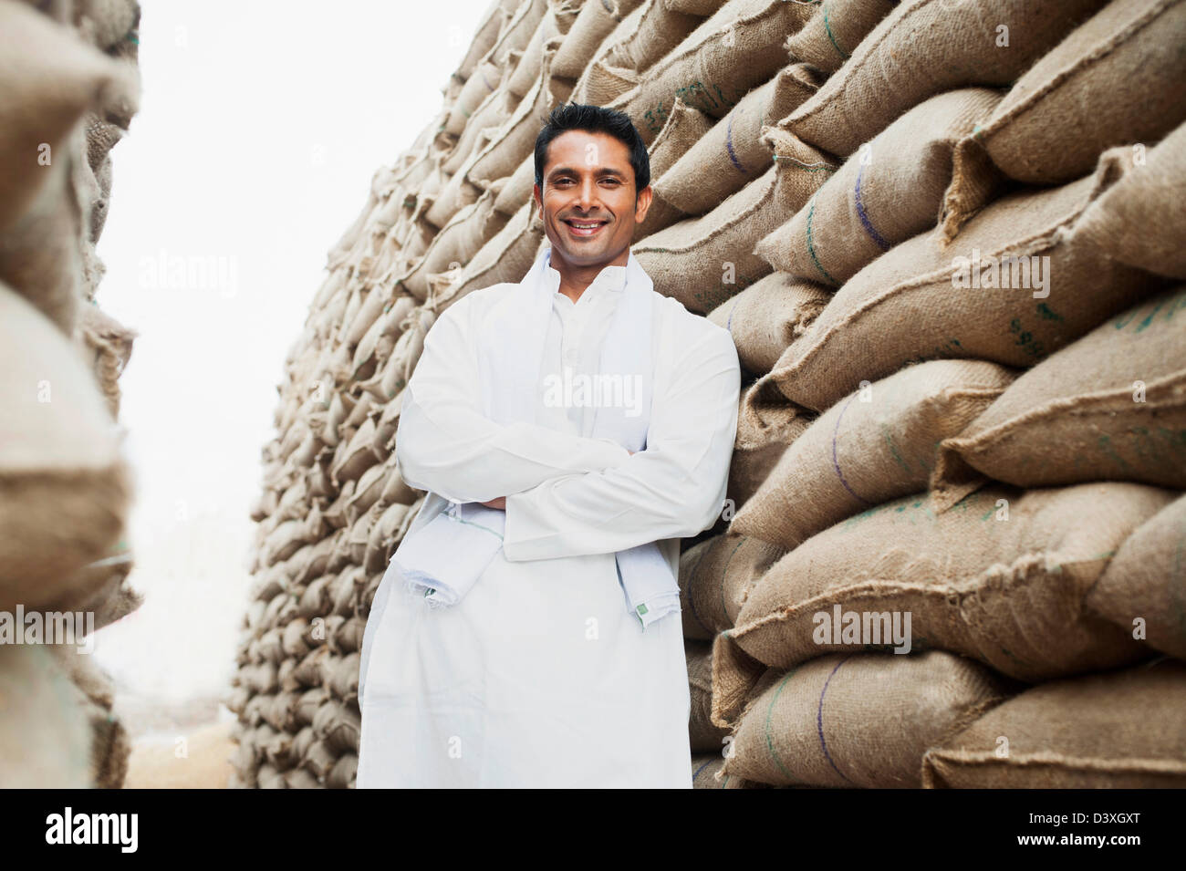 Man standing near stacks of wheat sacks in a warehouse, Anaj Mandi ...