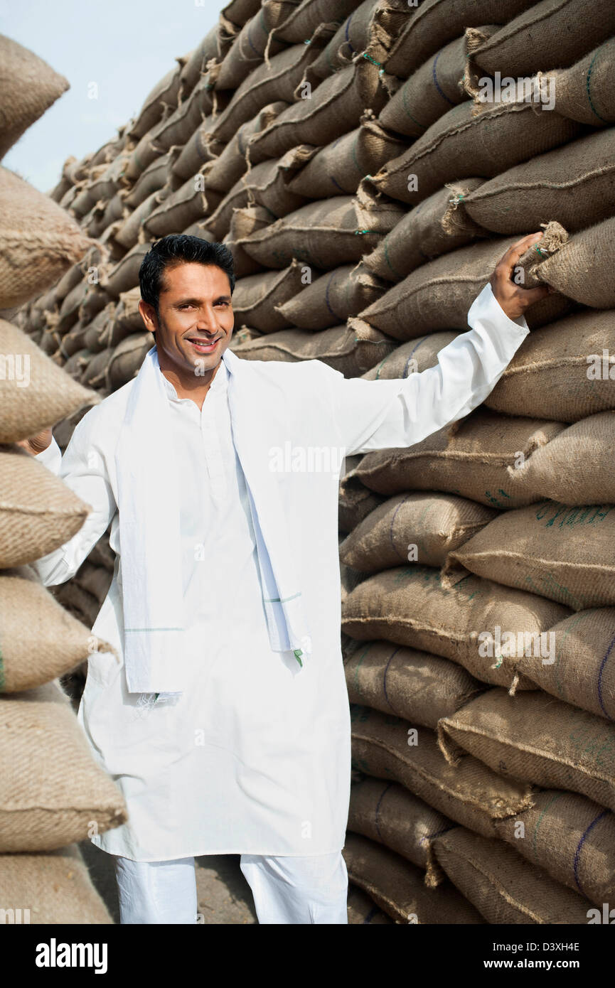 Man standing near stacks of wheat sacks in a warehouse, Anaj Mandi ...