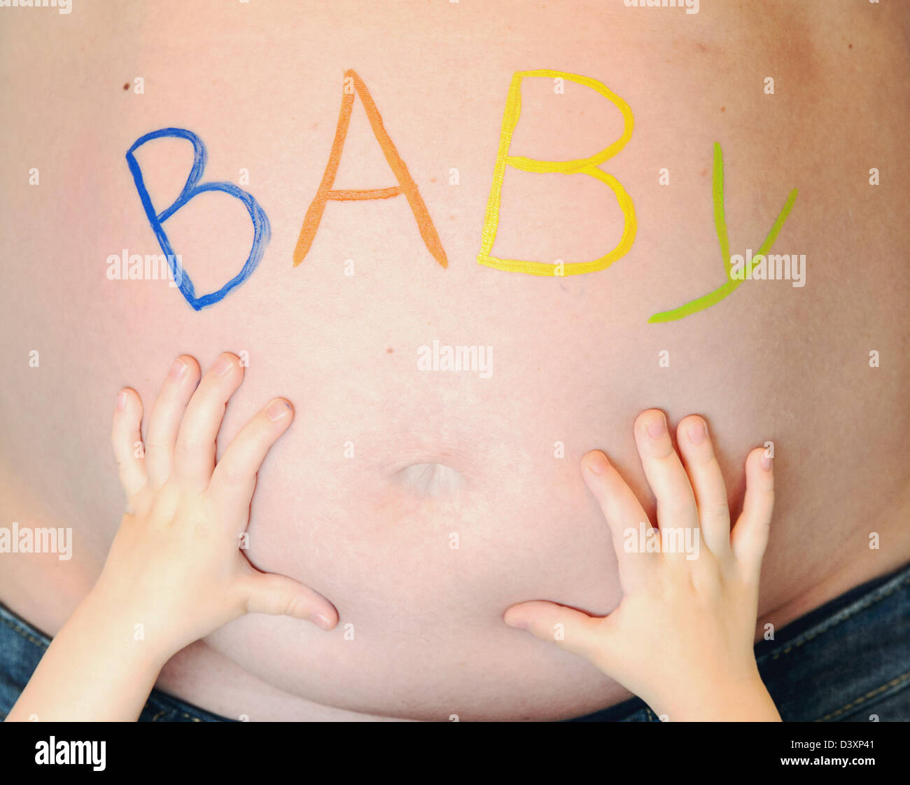 "Welcome Baby" is painted in colorful letters on the baby belly of a ...