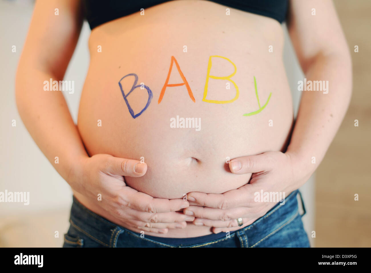 "Baby" is written in colorful letters on the baby belly of a pregnant ...