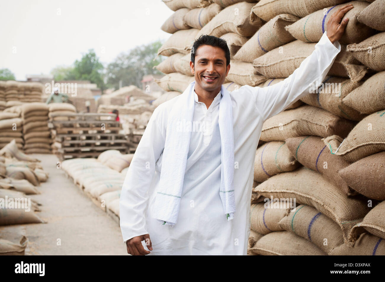 Man standing near stacks of wheat sacks in a warehouse, Anaj Mandi ...