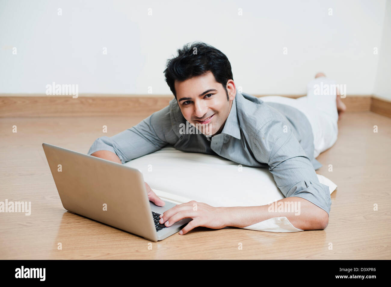Man lying on a floor and working on a laptop Stock Photo - Alamy