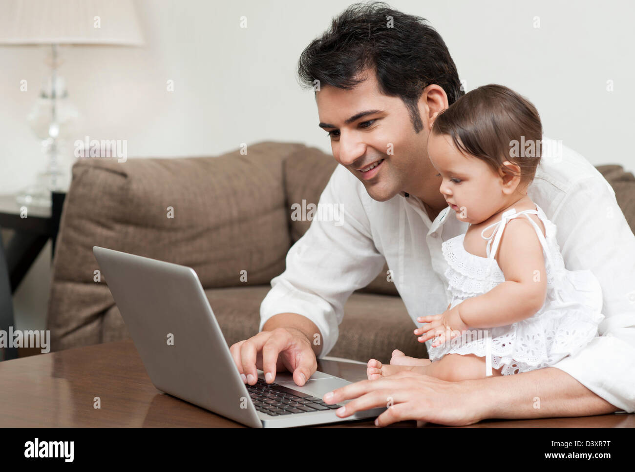Man using a laptop with his daughter sitting with him Stock Photo - Alamy