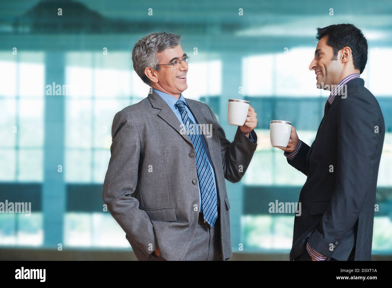 Two businessmen having coffee and smiling Stock Photo - Alamy