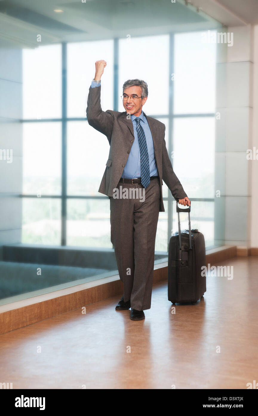 Businessman pulling a trolley bag and smiling Stock Photo - Alamy