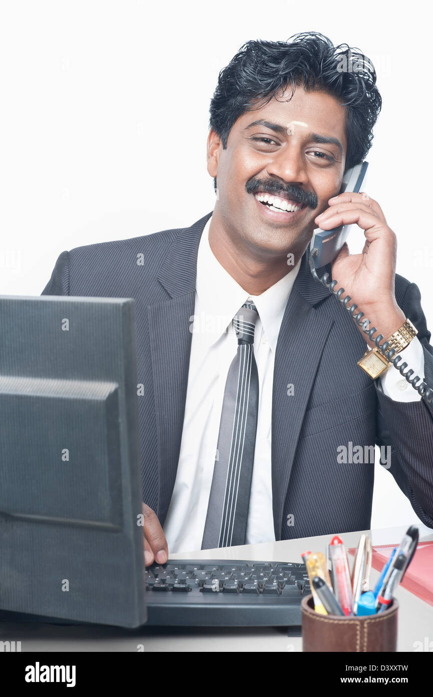 South Indian businessman using a computer and a phone Stock Photo - Alamy