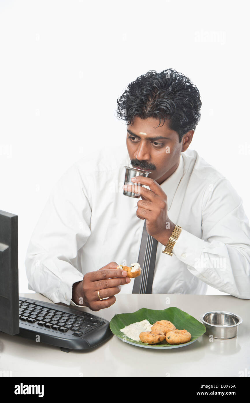 South Indian businessman working in an office and having food Stock ...
