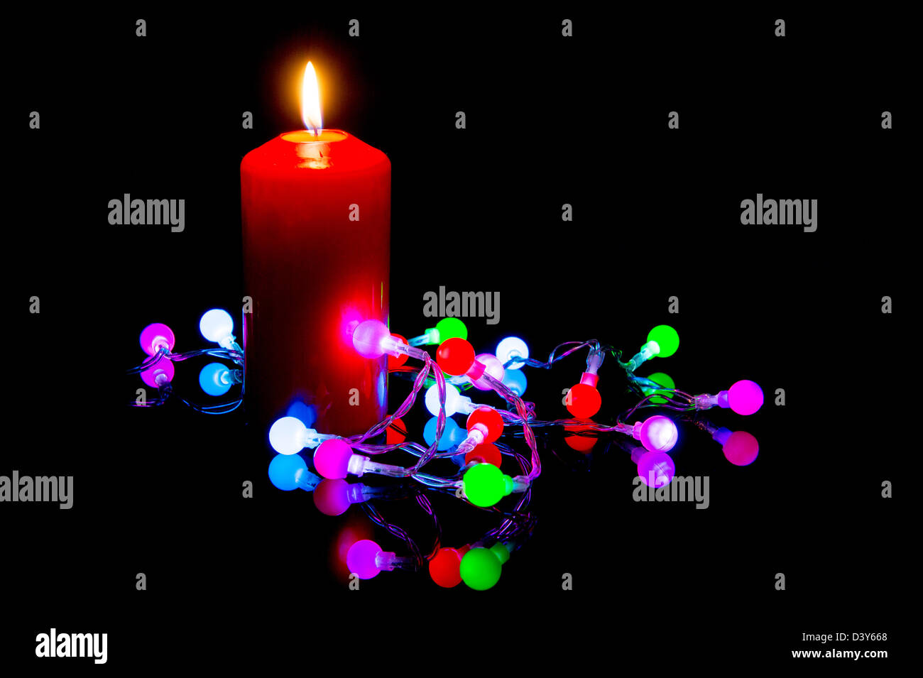 Colorful Christmas lights with reflection and burning candle on back ...