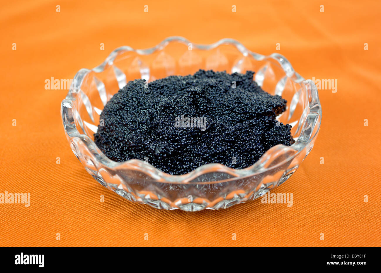 A small glass bowl filled with black caviar on a cloth background Stock ...