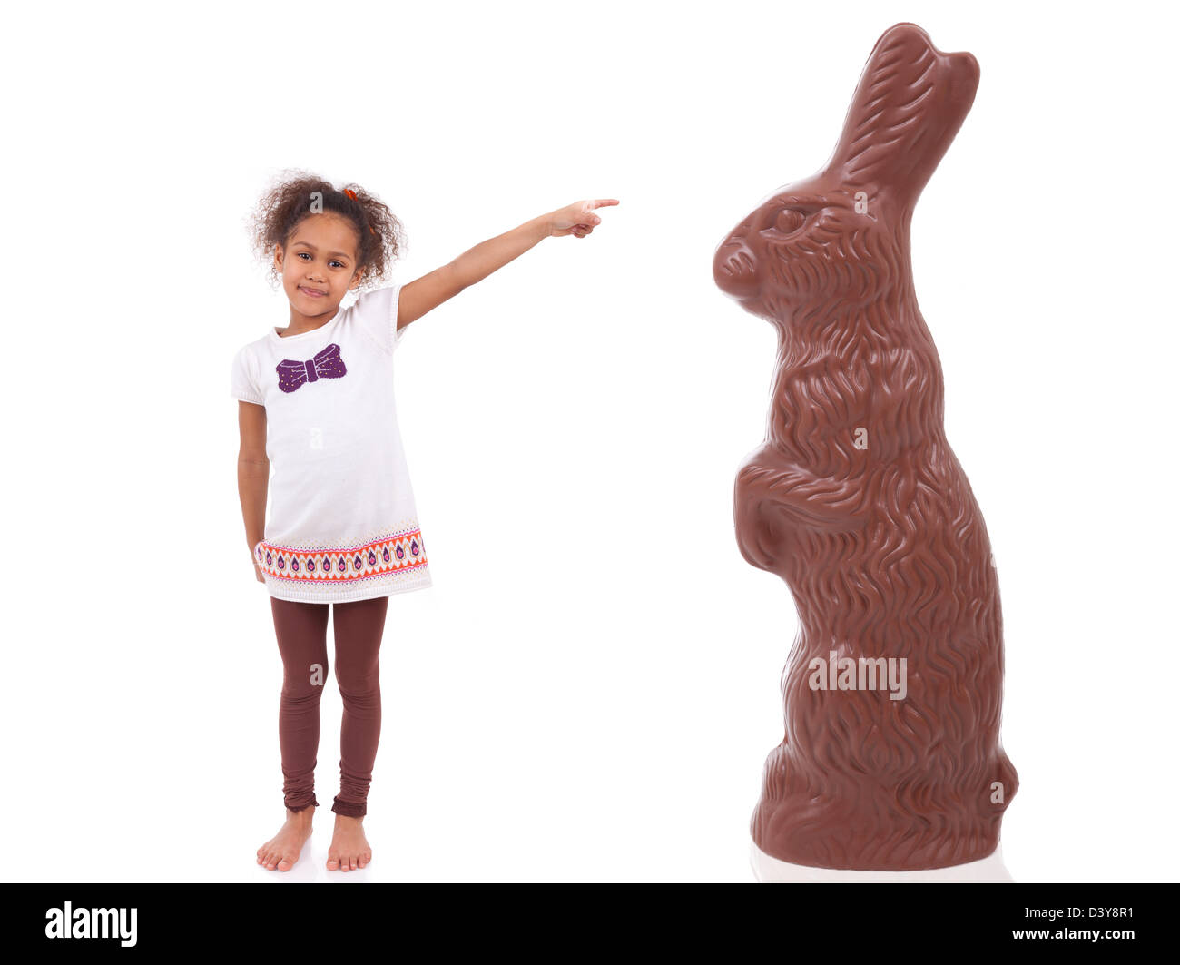 African Asian girl pointing a giant chocolate rabbit, isolated on white ...
