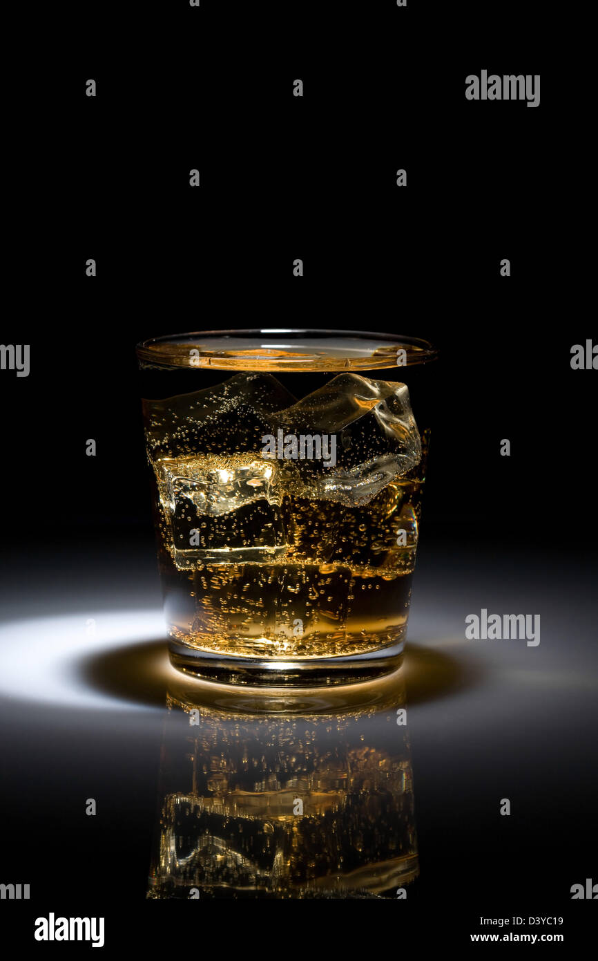 Whiskey over ice in a clear glass and lit by spotlight Stock Photo - Alamy