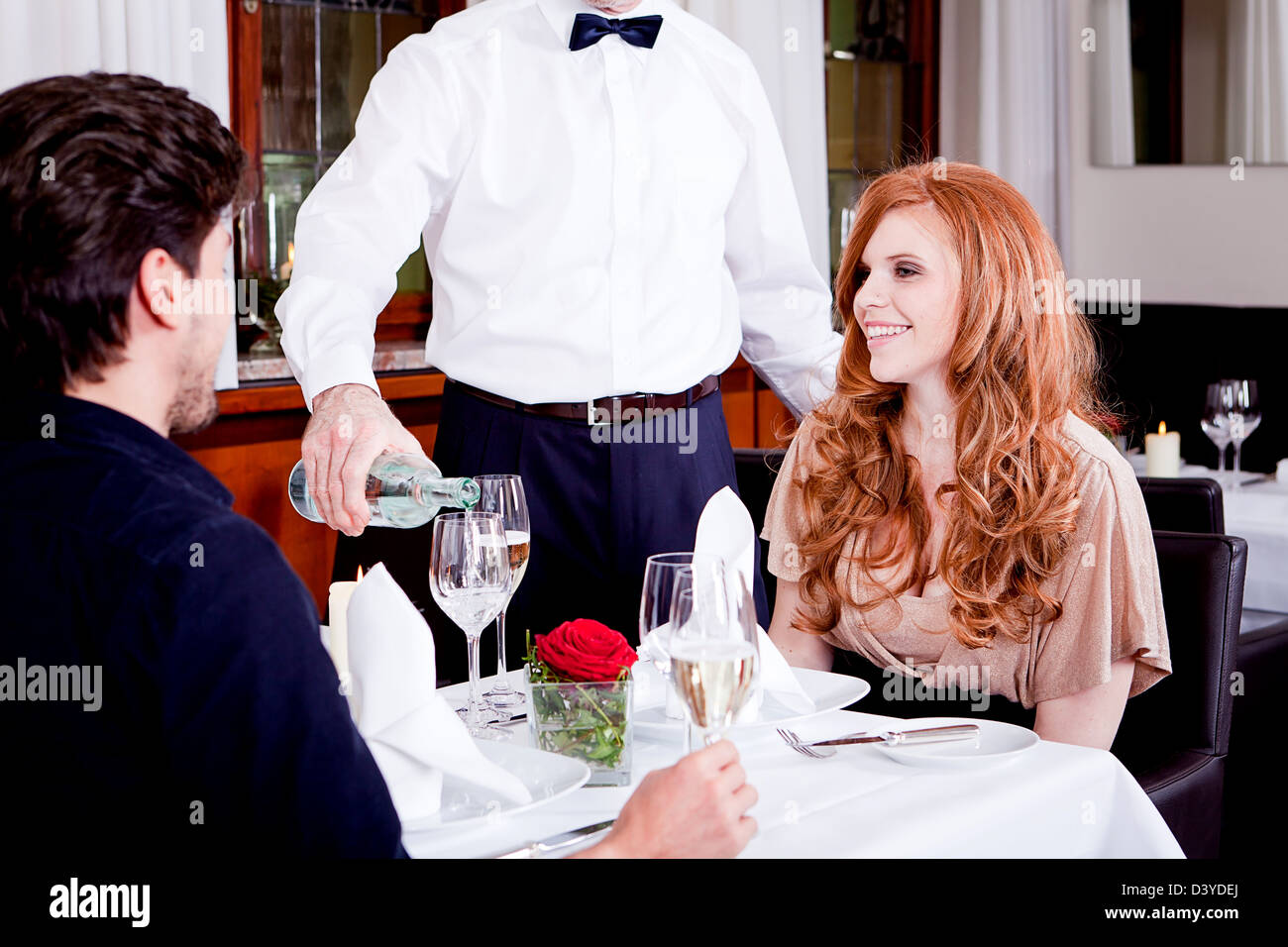 man and woman for dinner in restaurant waiter serving mineral water ...