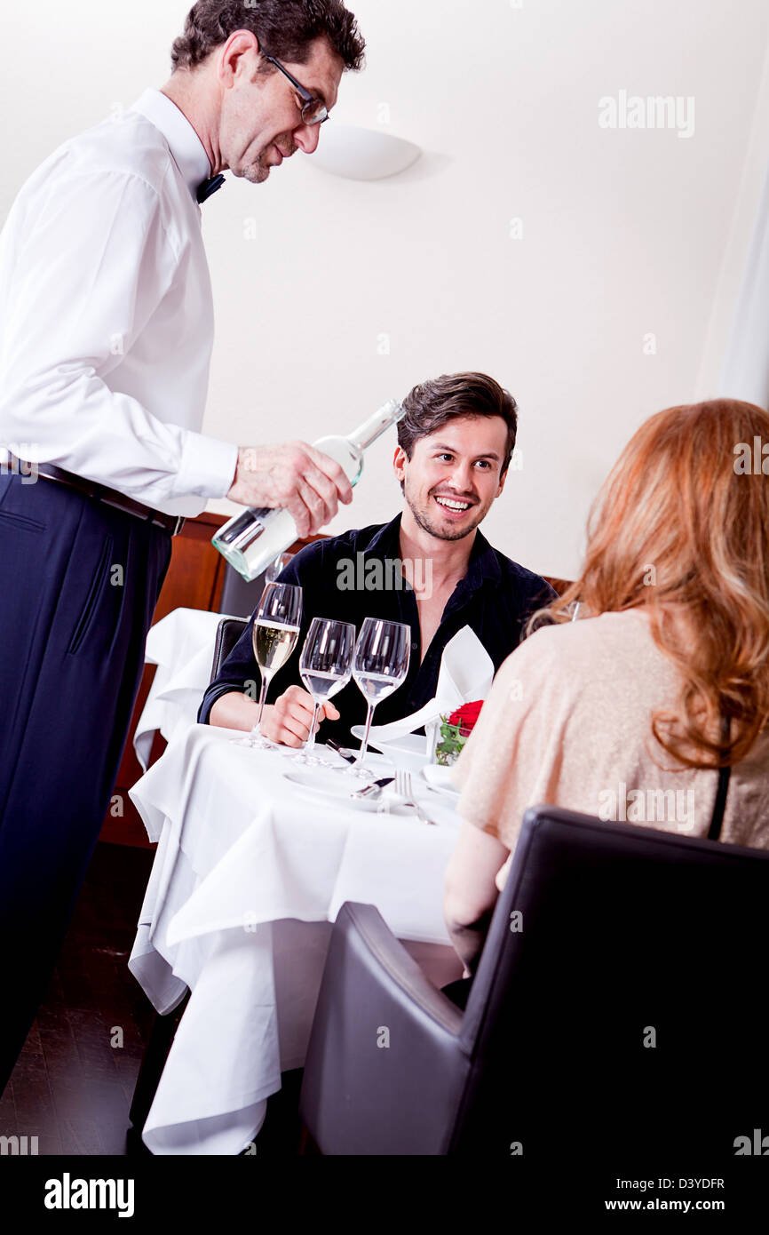 man and woman for dinner in restaurant waiter serving mineral water ...