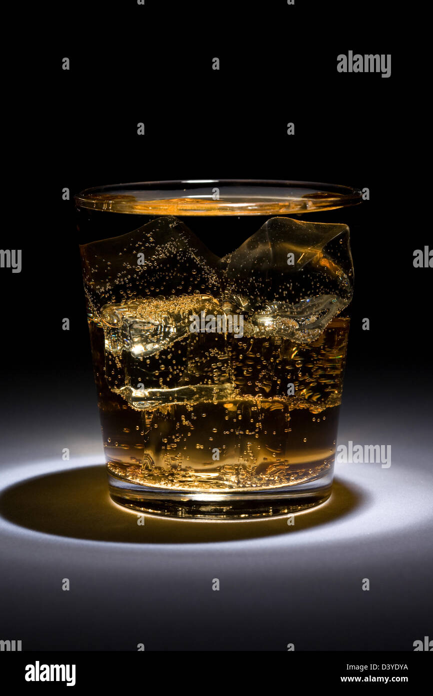 Whiskey over ice in a clear glass and lit by spotlight Stock Photo - Alamy