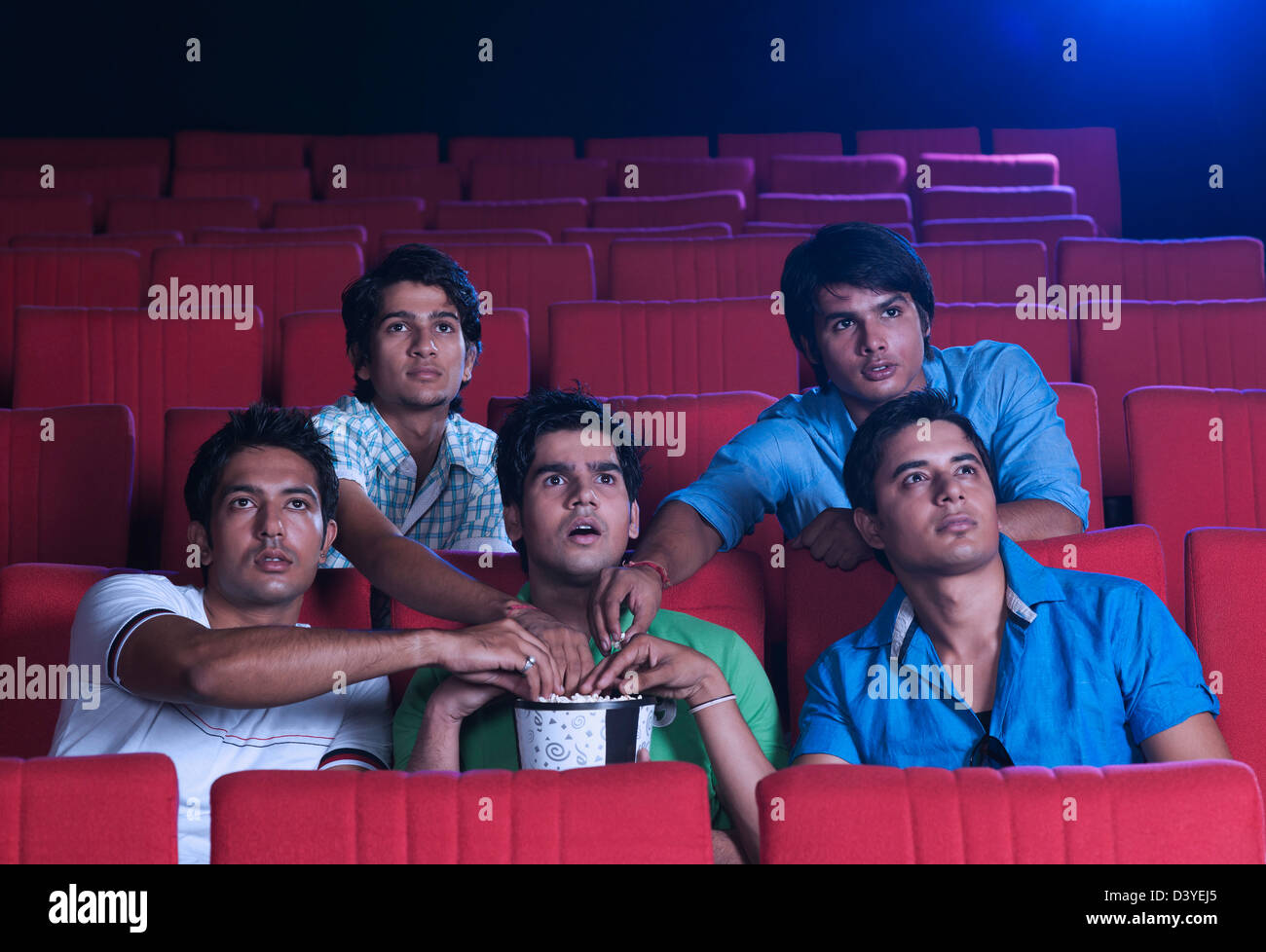 Youngsters enjoying movie with popcorns in a cinema hall Stock Photo ...