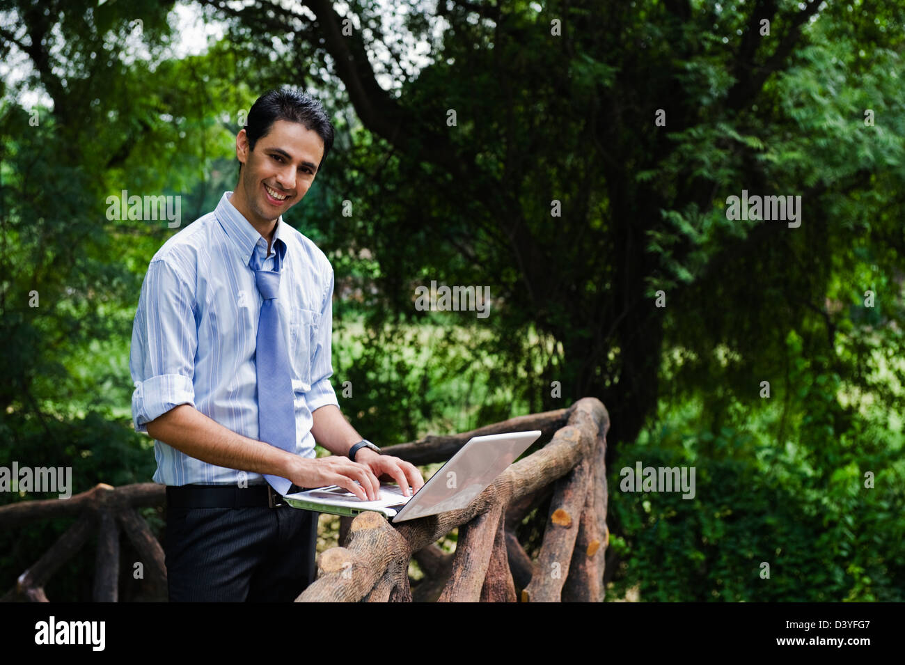 Businessman using a laptop in a park Stock Photo - Alamy