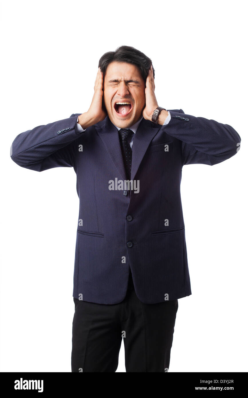 Businessman screaming with hands over his ears Stock Photo - Alamy
