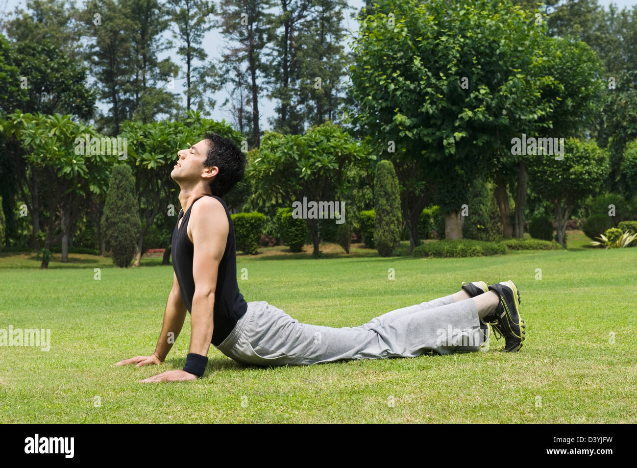 Man doing snake pose in a park Stock Photo - Alamy