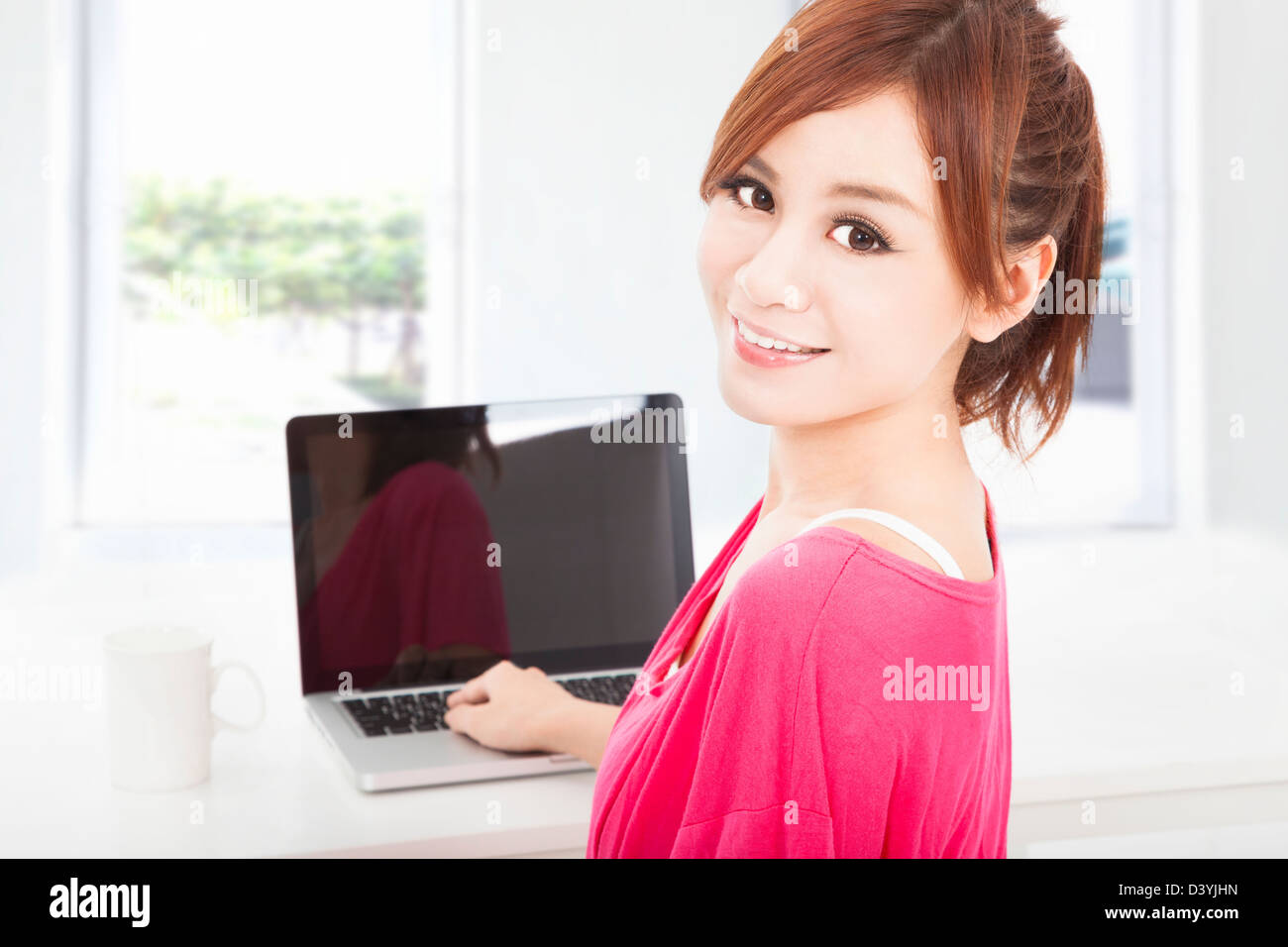 smiling young woman sitting with laptop computer Stock Photo - Alamy
