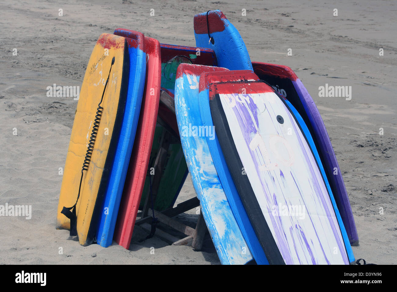 Stacked body boards or boogie boards on a sand covered beach on the ...