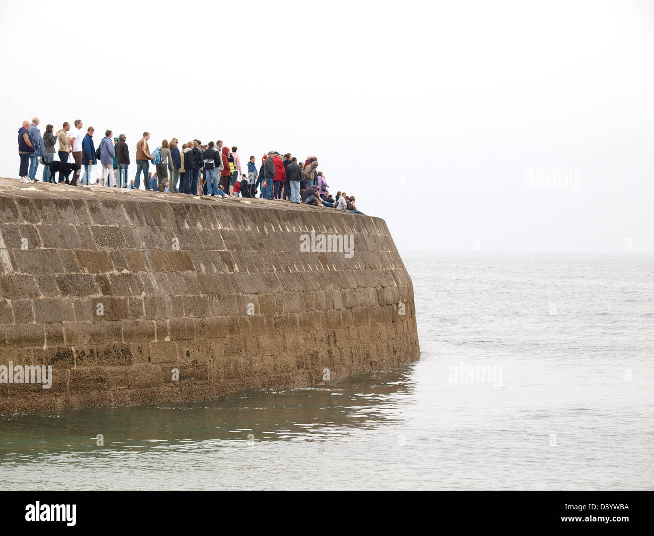 A crowd of people standing at end of the Cobb looking out to sea Stock ...