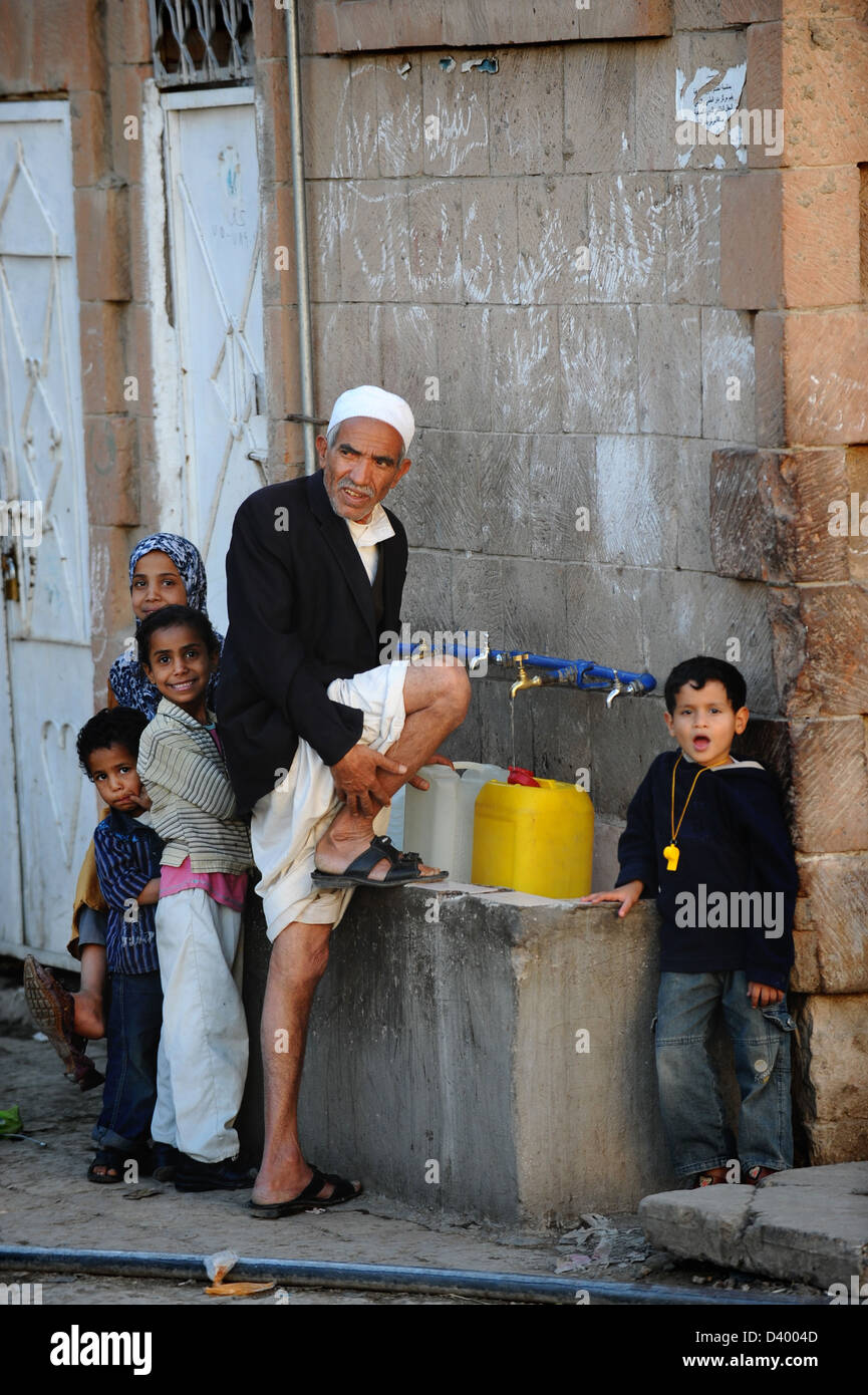 A man fills water containers at a communal water tap in the old part of ...