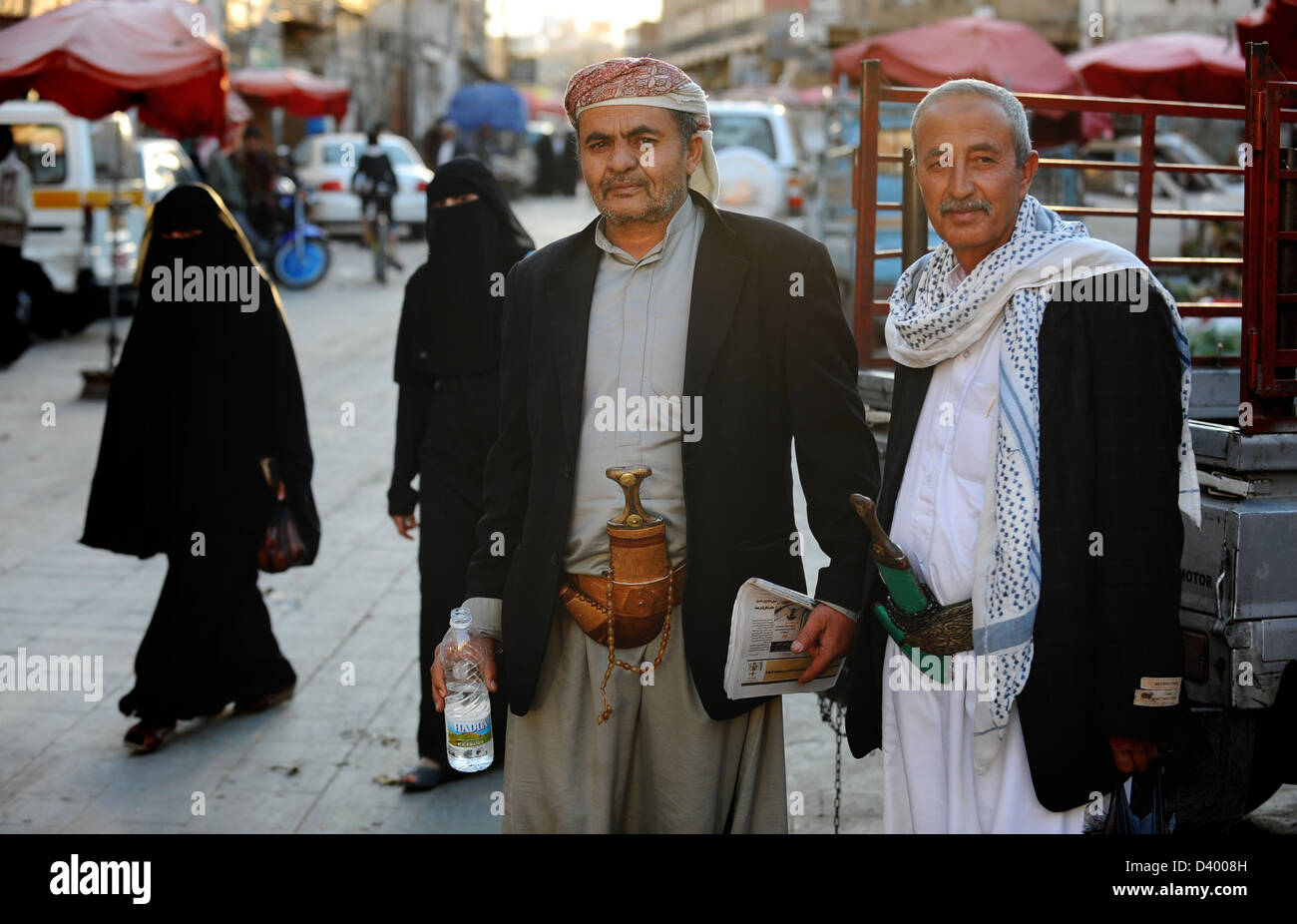 Two men in traditional clothes in the old city of Sana'a, Yemen. Veiled ...