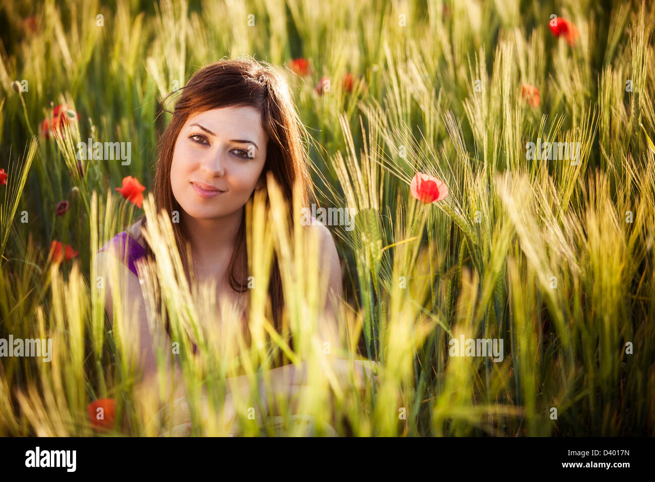 Young beautiful girl posing in a green field Stock Photo - Alamy
