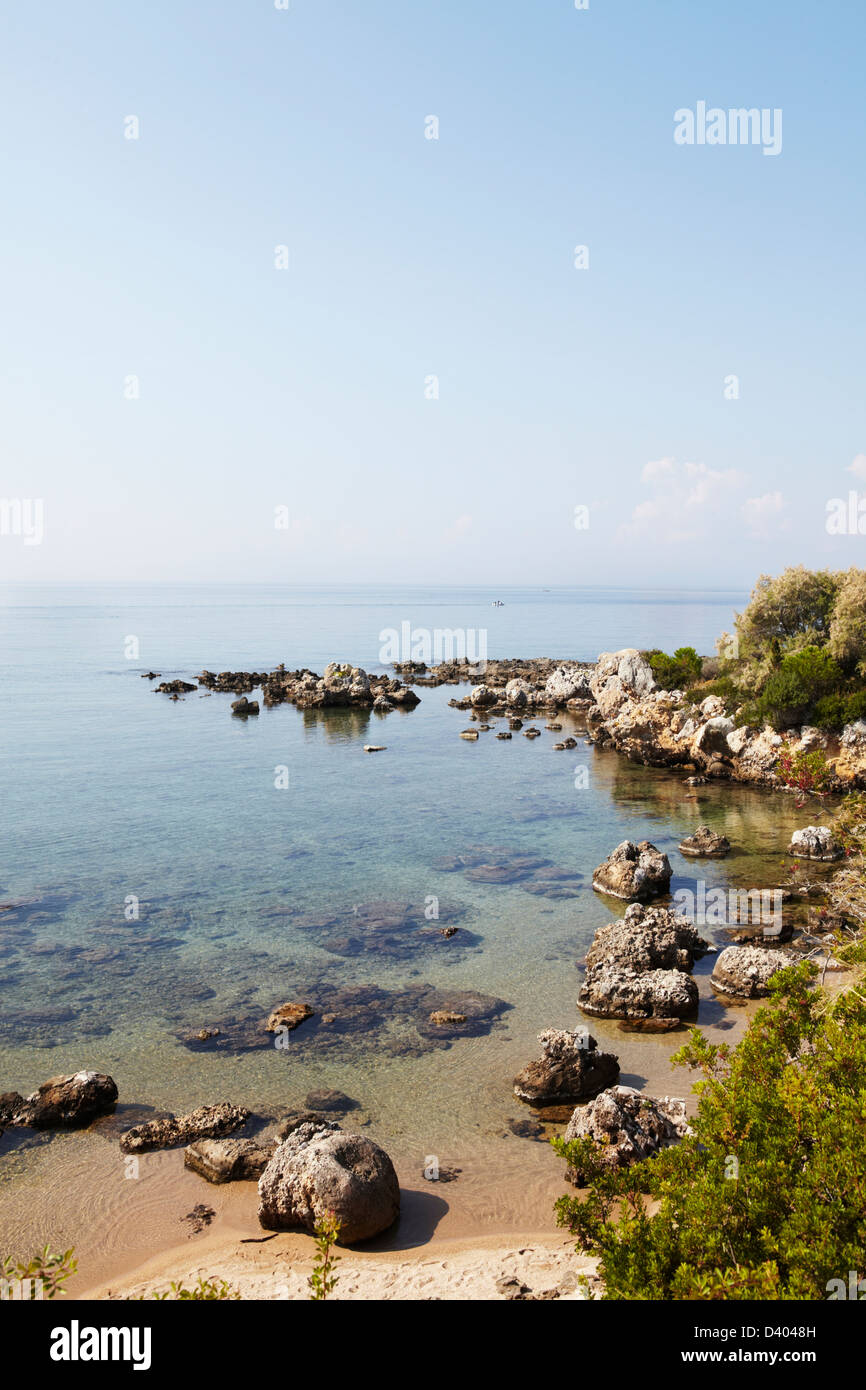 A calm still view across a sheltered beach in Greece with large blue ...