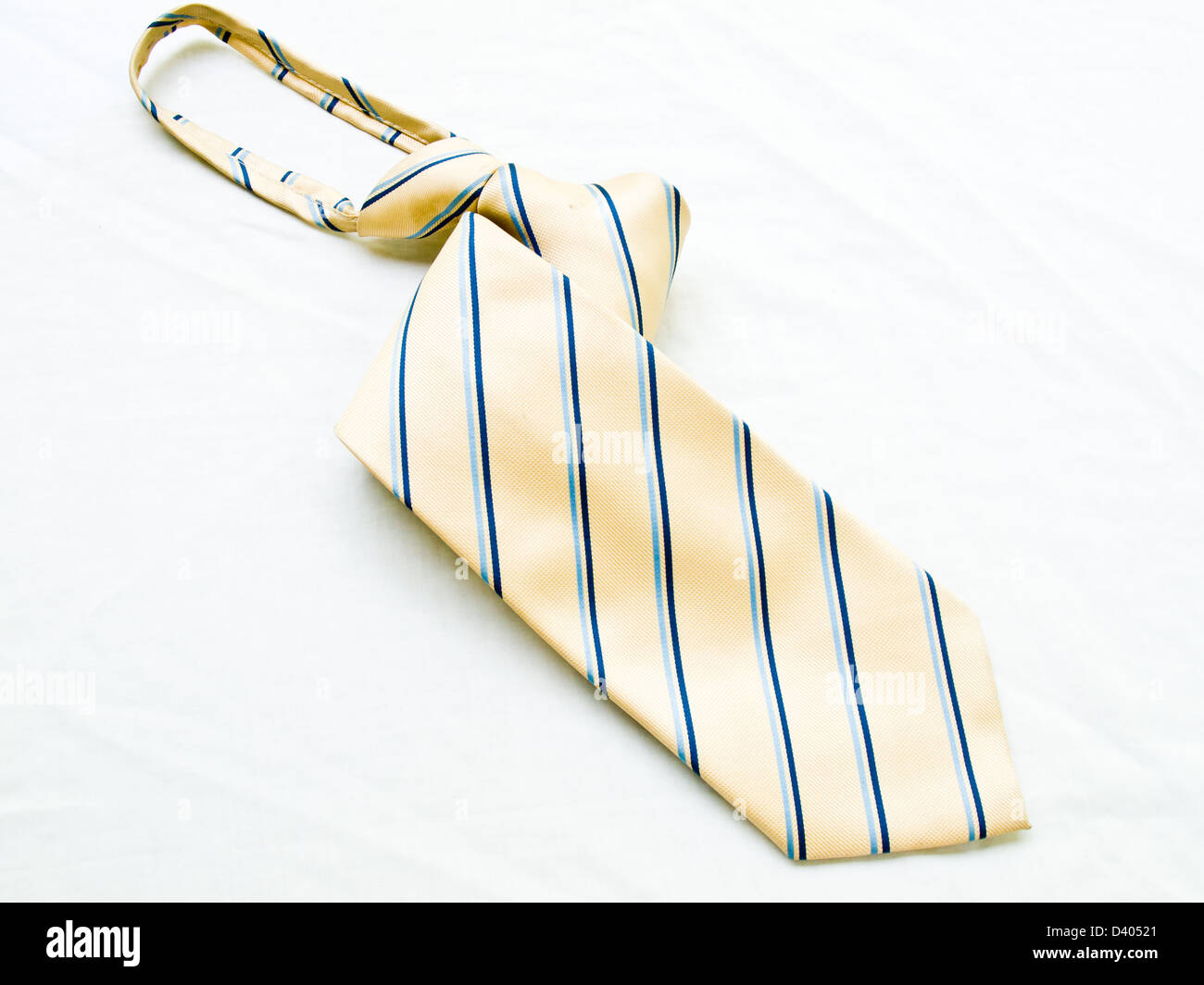 A rolled up striped yellow and blue tie isolated on white background ...