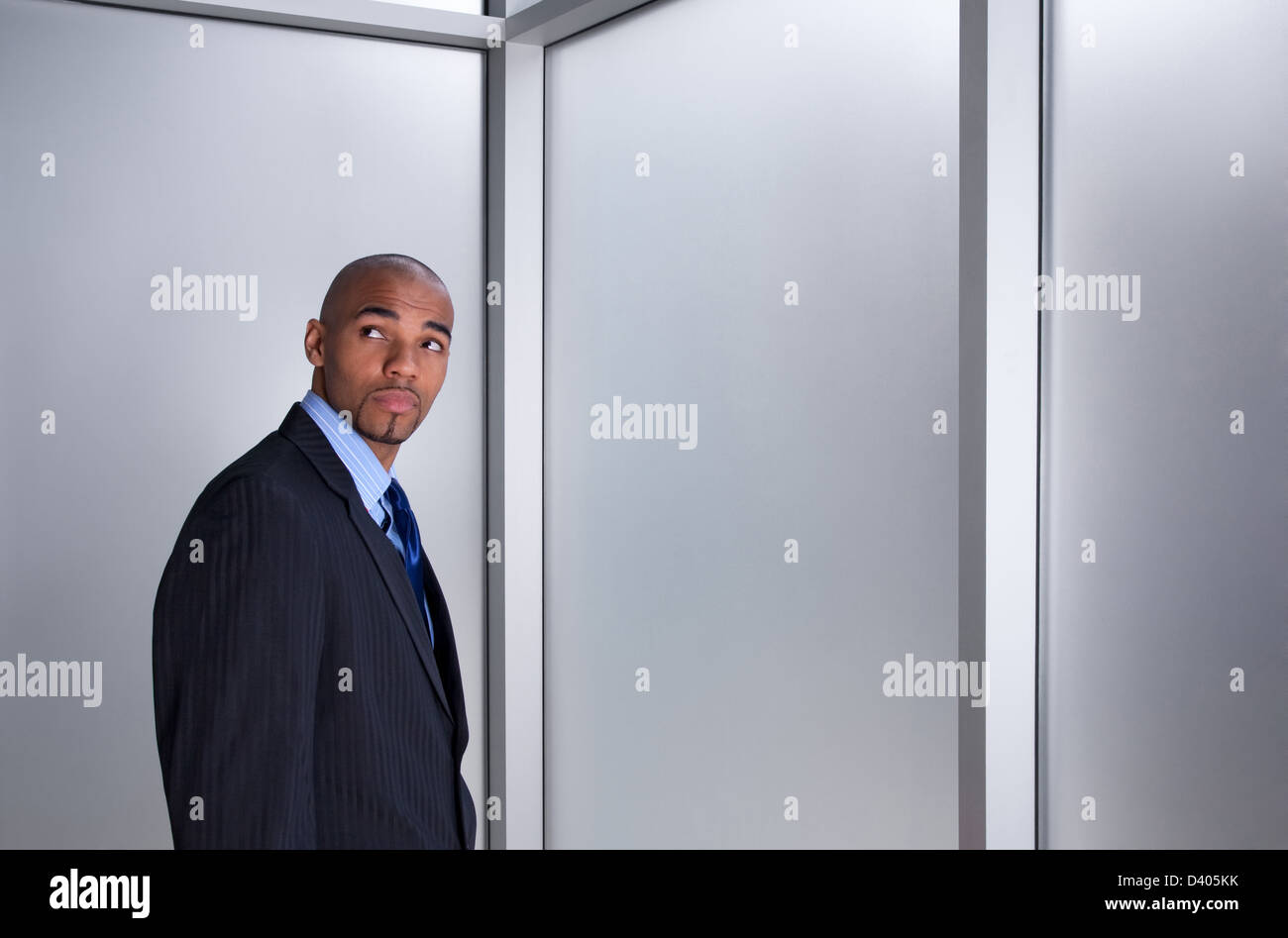 Young businessman looking anxious and worried, standing beside a window ...