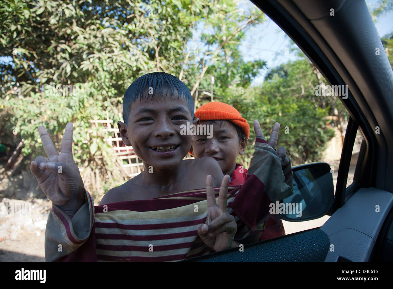 Two cheeky boys peering through a car window at a festival at Win Sein ...