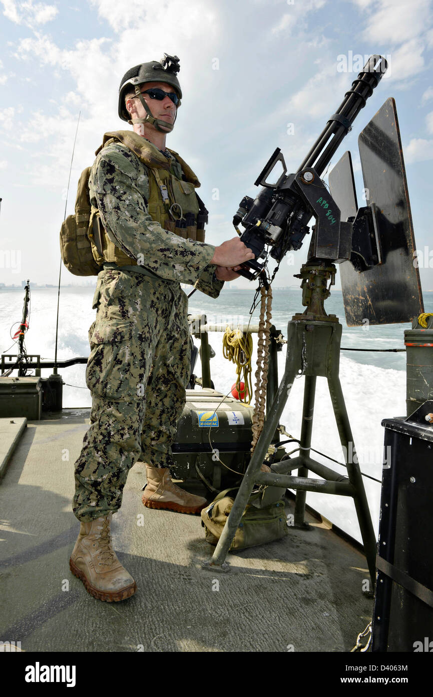 US Navy SEAL mans a Mark 44 minigun aboard a riverine command boat ...