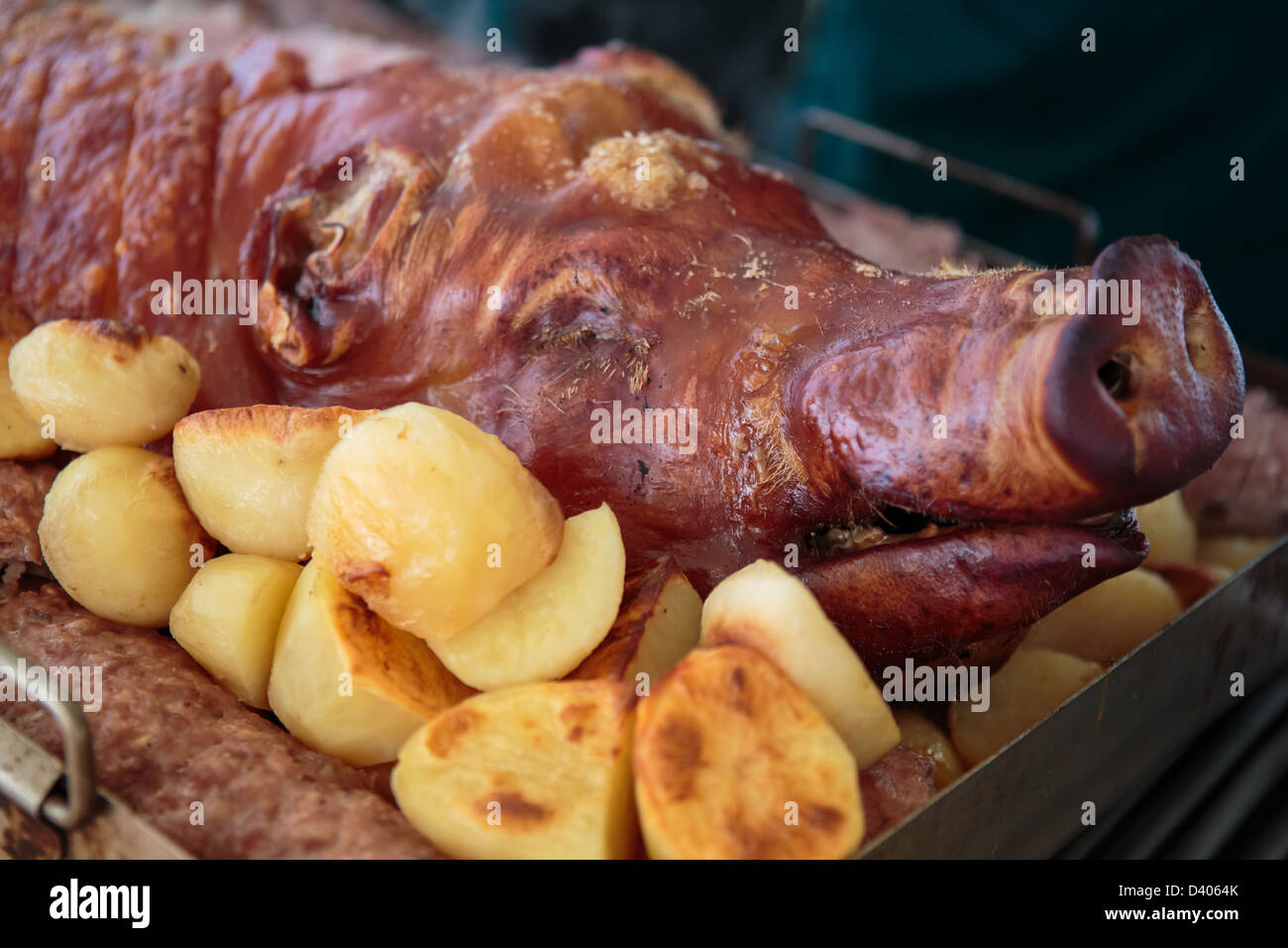 Hog roast - pigs head and roast potatoes Stock Photo - Alamy