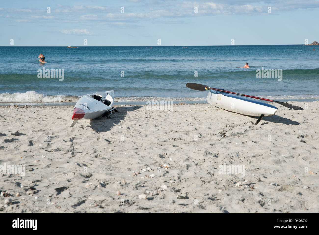 Surf skis lie on beach with surfers paddling out in background on a day ...